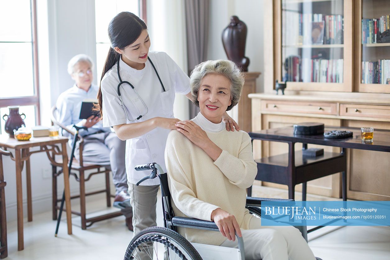 Chinese nursing assistant taking care of senior woman in wheel chair ...