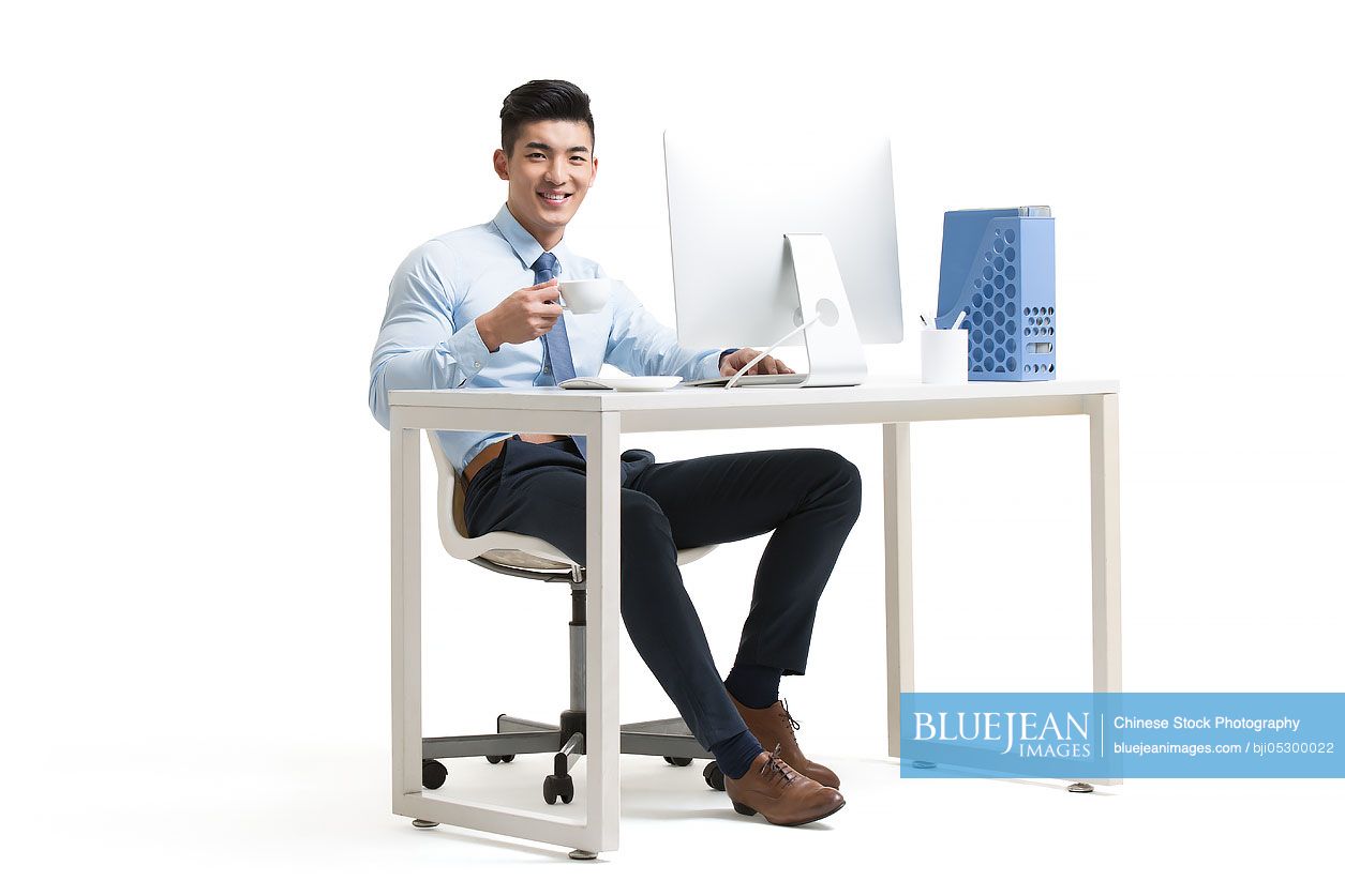 Young Chinese businessman working with computer in office while drinking coffee-High-res stock ...