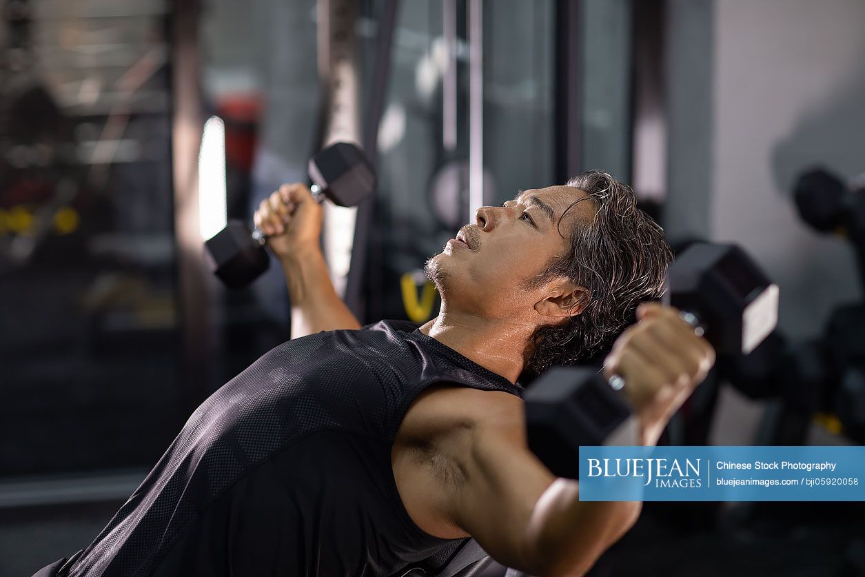 Mature Chinese man working out with hand weights at gym-High-res stock ...