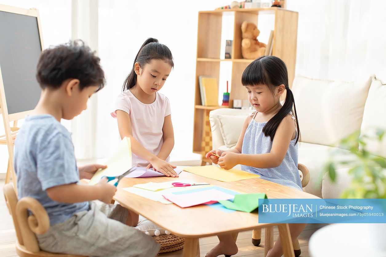Cute Chinese children doing paper craft in living room-High-res stock photo for download