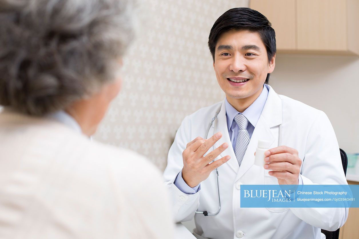 Chinese doctor explaining dosage of medicine to patient-High-res stock photo for download