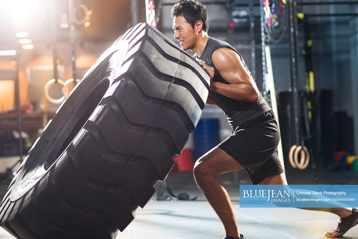 Young Chinese man pushing large tire in crossfit gym-High-res stock ...