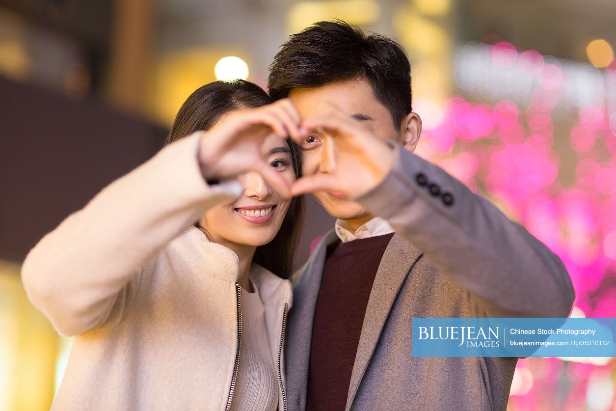 Cheerful young Chinese couple making heart shape with their hands-High ...