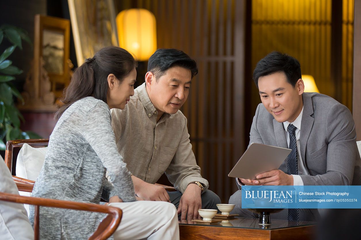 Confident Chinese financial consultant talking with mature couple-High ...