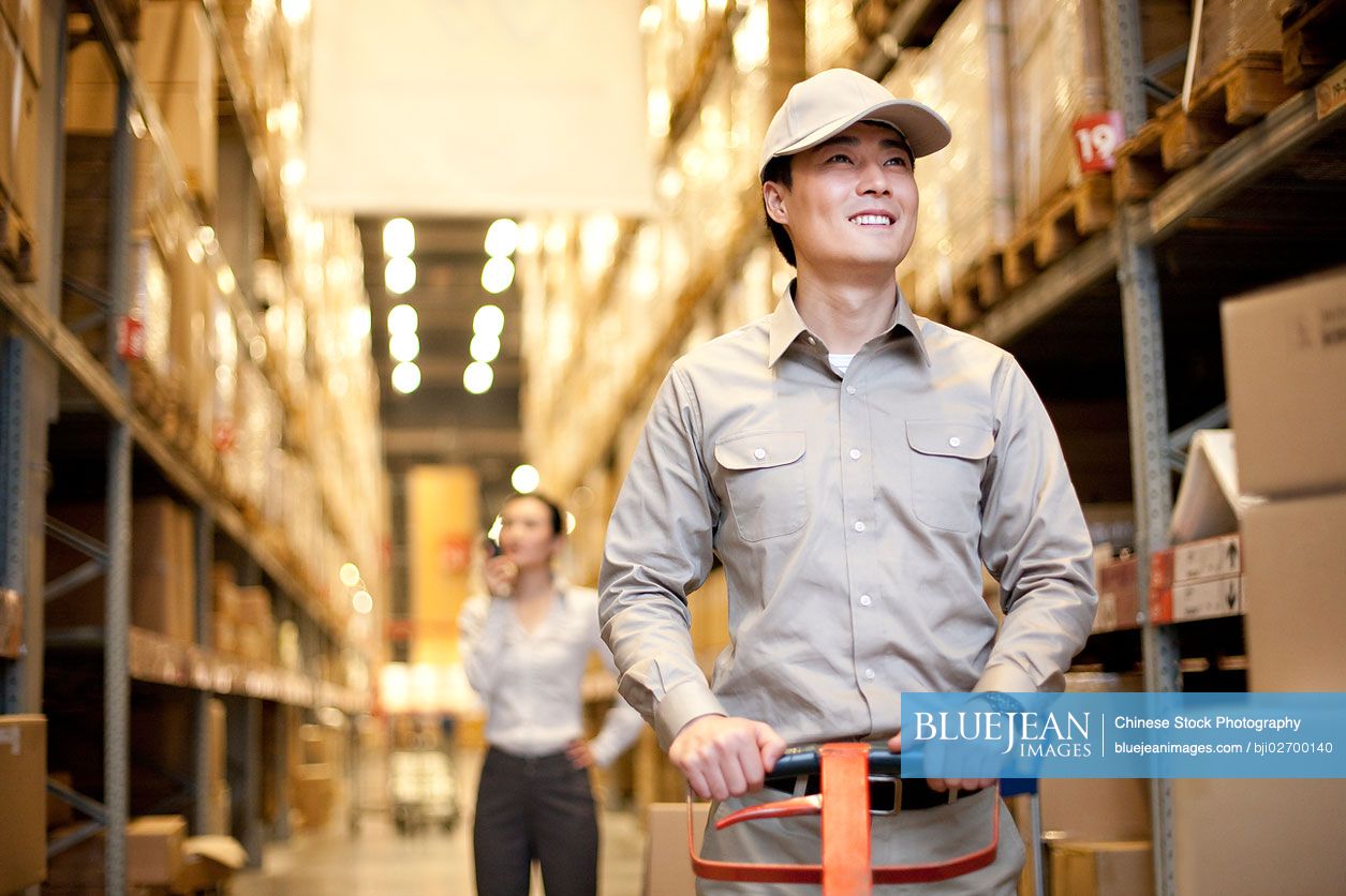 Male Chinese warehouse with Chinese businesswoman in the background ...