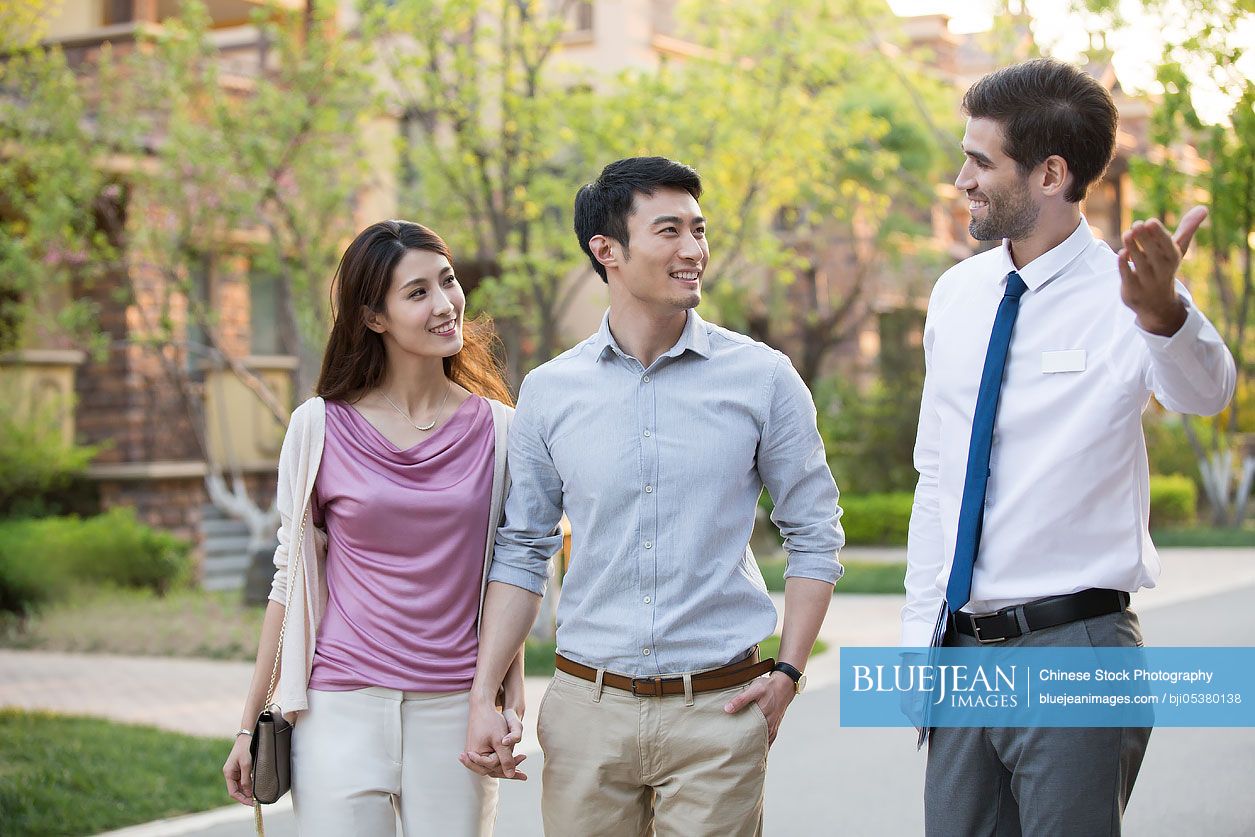 Happy young Chinese couple talking with confident businessman-High-res ...