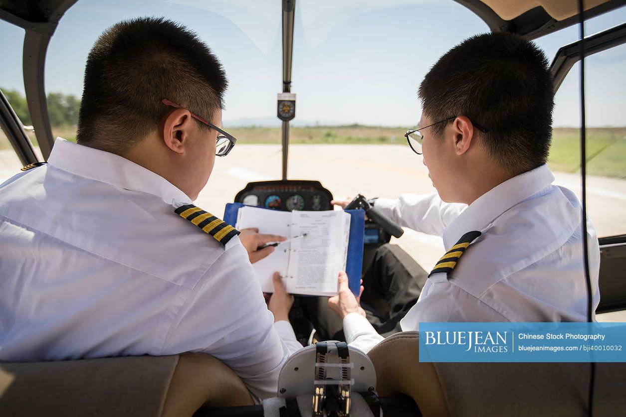 Chinese pilot teaching trainee to operate control panel in cockpit-High ...