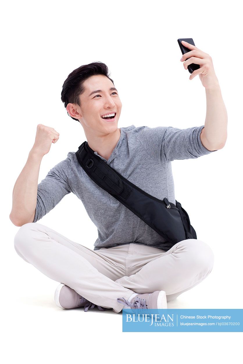Excited male Chinese college student with smart phone-High-res stock ...